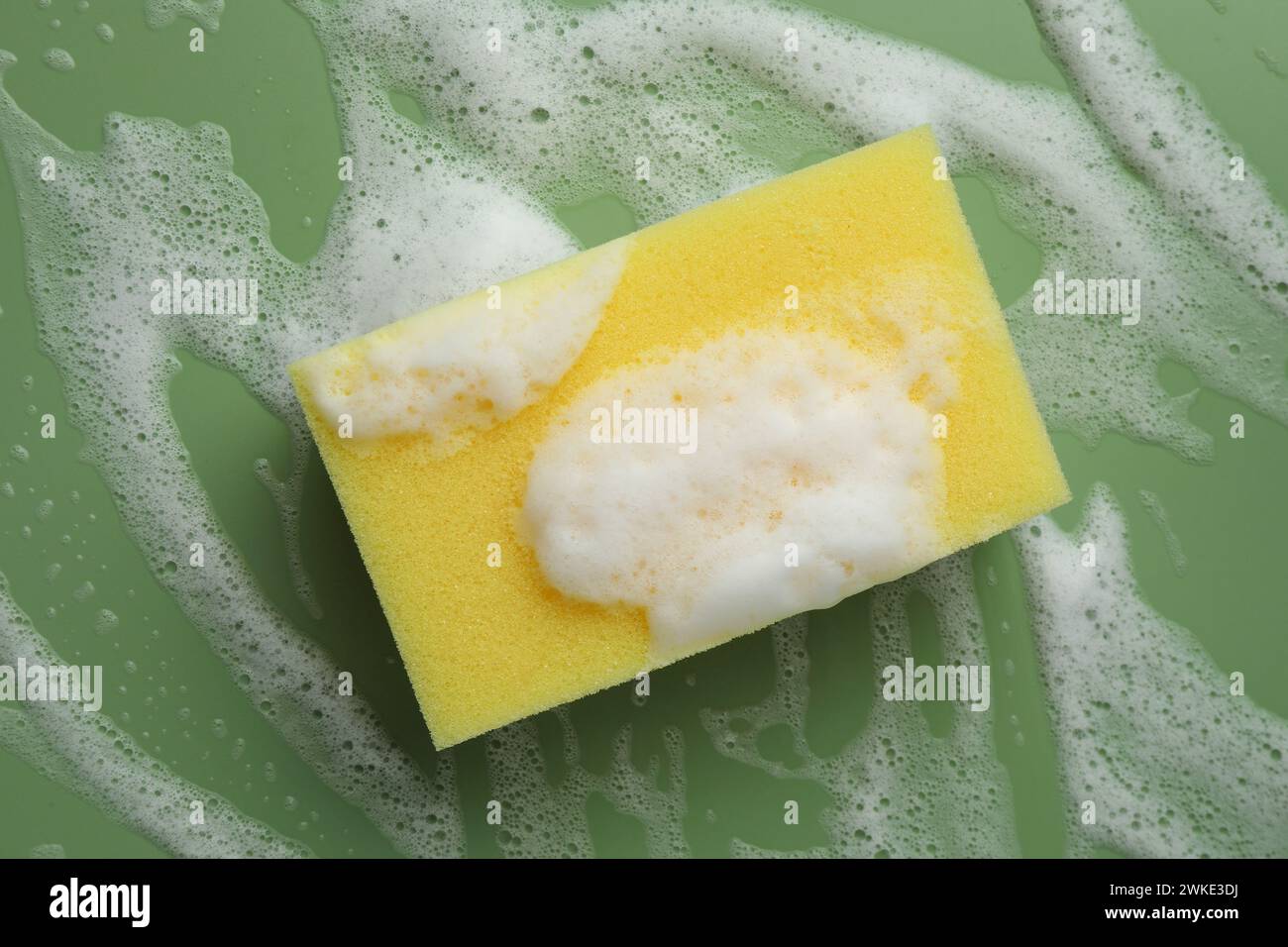 Yellow sponge with foam on green background, top view Stock Photo - Alamy
