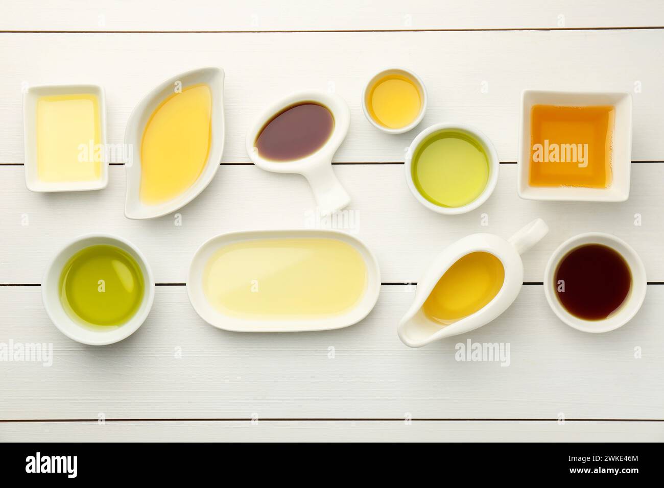 Vegetable fats. Different cooking oils on white wooden table, flat lay ...