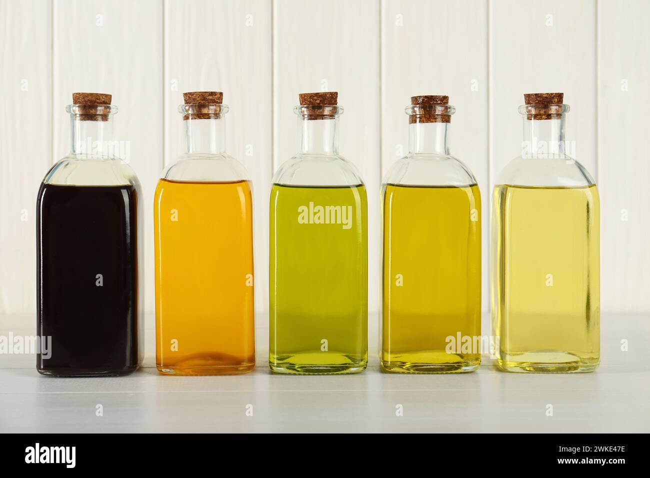 Vegetable fats. Different cooking oils in glass bottles on white wooden ...