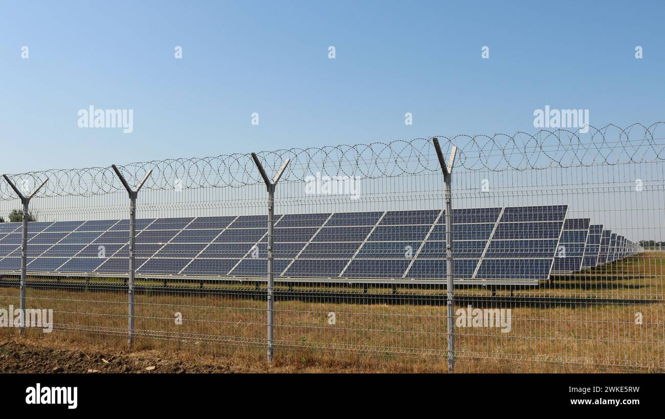 a complex of solar panels behind a barbed wire fence in a field under a ...