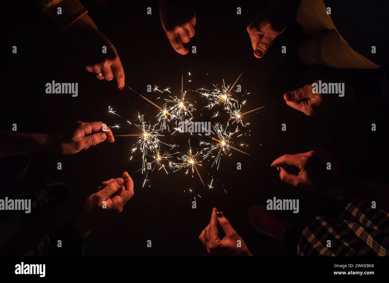 Group of people celebrate holding burning sparklers in their hands ...