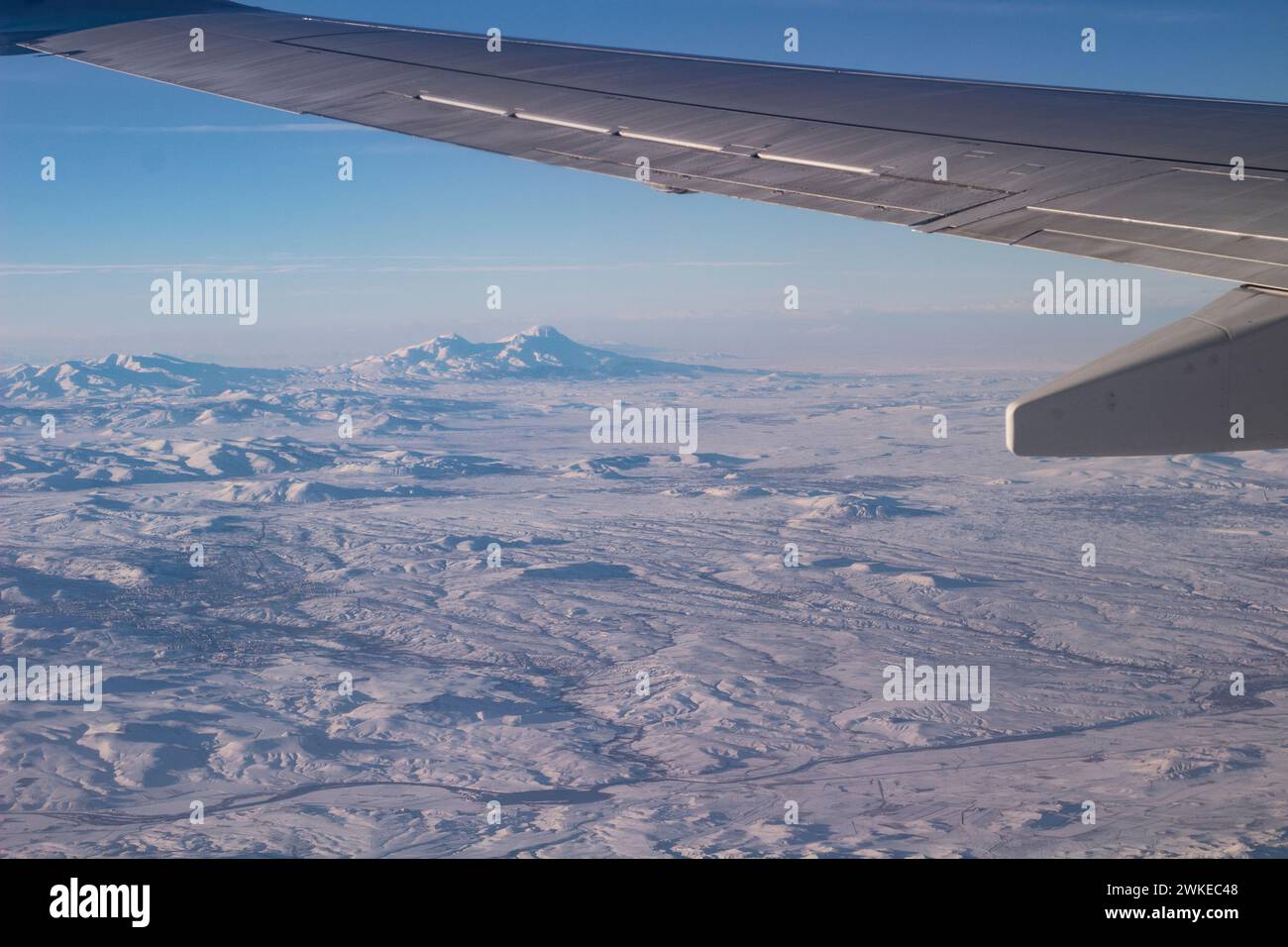 The sky with clouds and mountains in snow. Photo taken from an airplane ...