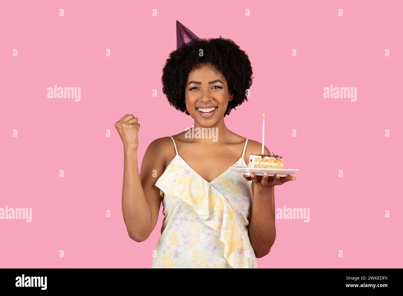 Exuberant African American woman with curly hair wearing a party hat ...