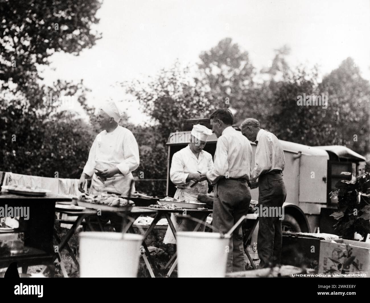 Henry Ford and Harvey Firestone assisting two chefs by peeling potatos ...