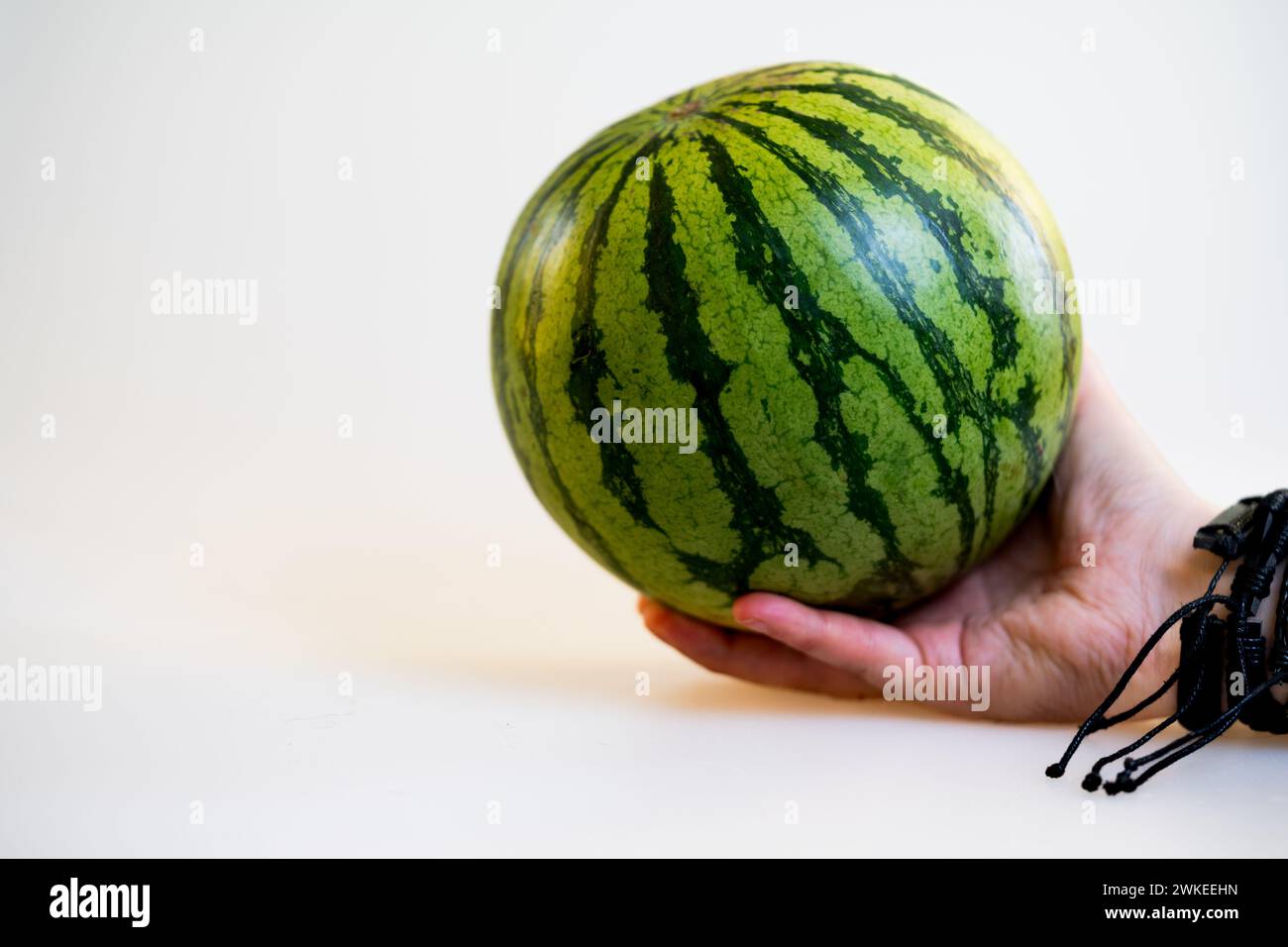 hand grabbing a round watermelon on white background Stock Photo - Alamy