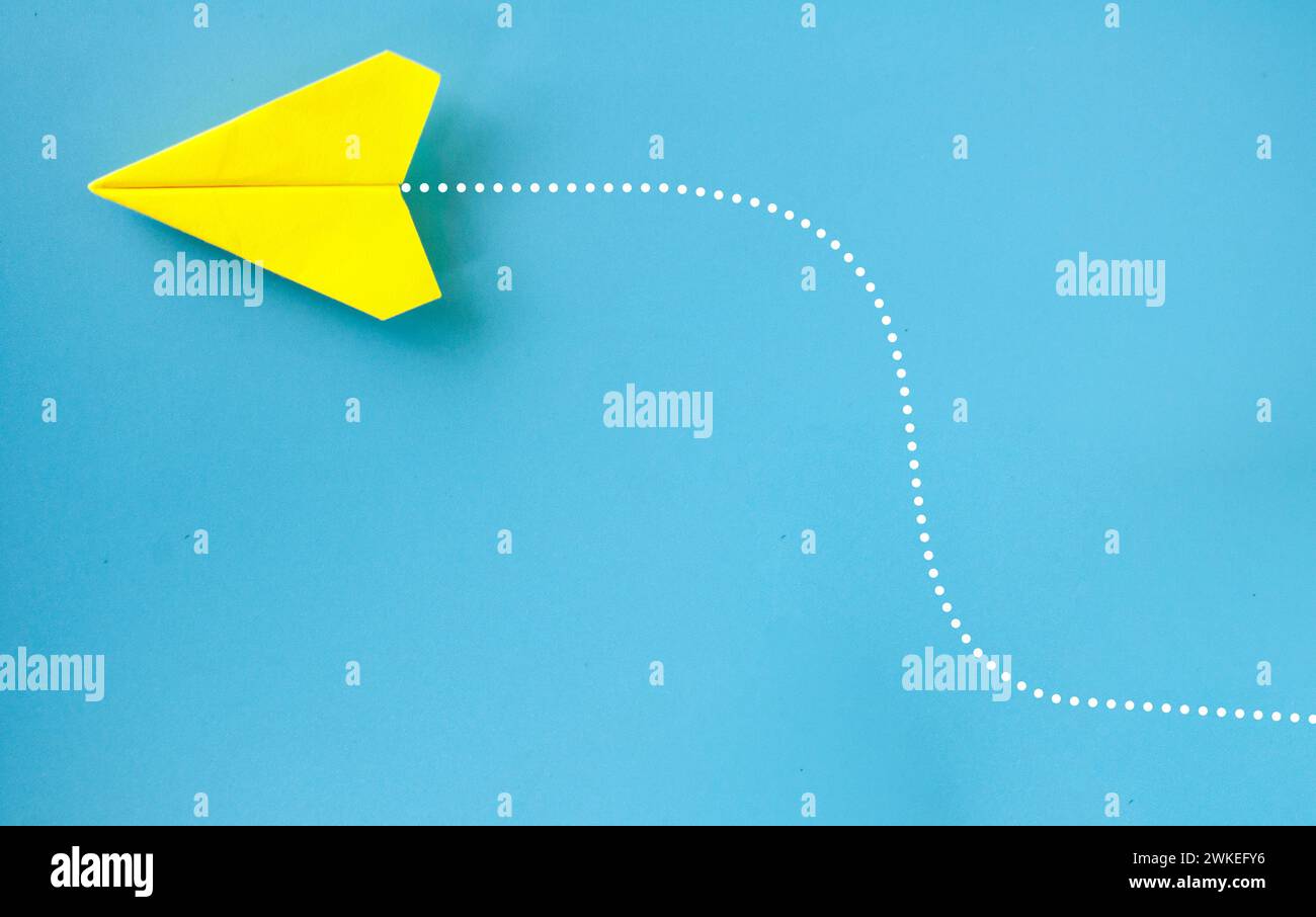 Top view of yellow paper airplane making turning on blue background ...