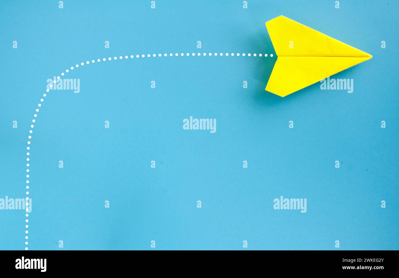 Top view of yellow paper airplane making turning on blue background ...