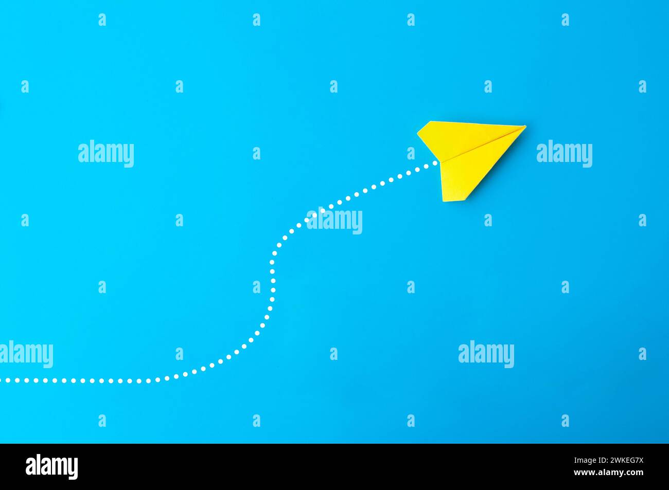 Top view of yellow paper airplane with line dots on blue background ...