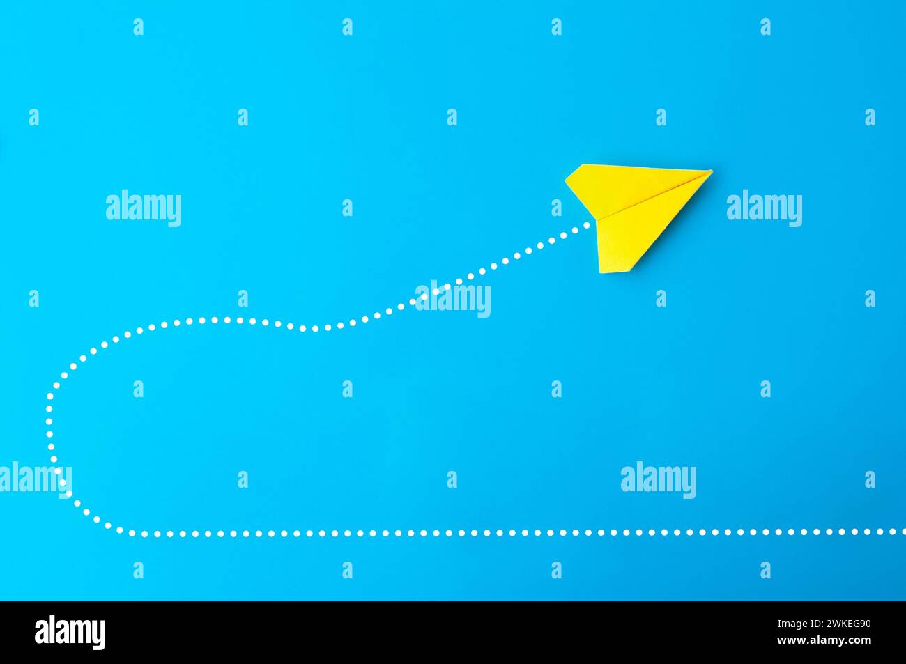 Top view of yellow paper airplane making a U turn on blue background ...