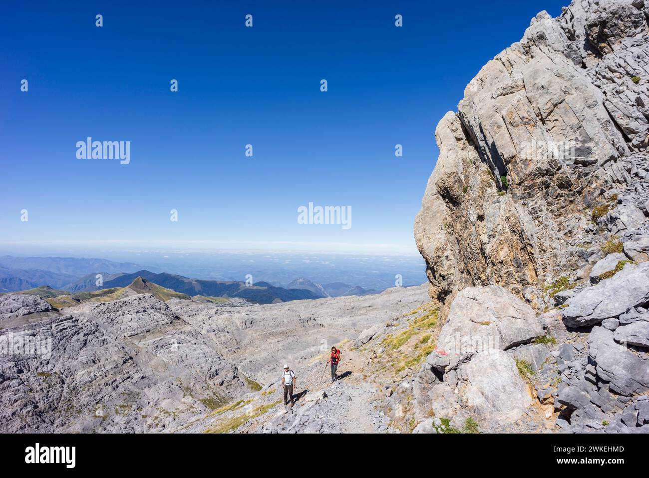 hiker advancing through the limestone relief of the Arres de Anie, Anie ...
