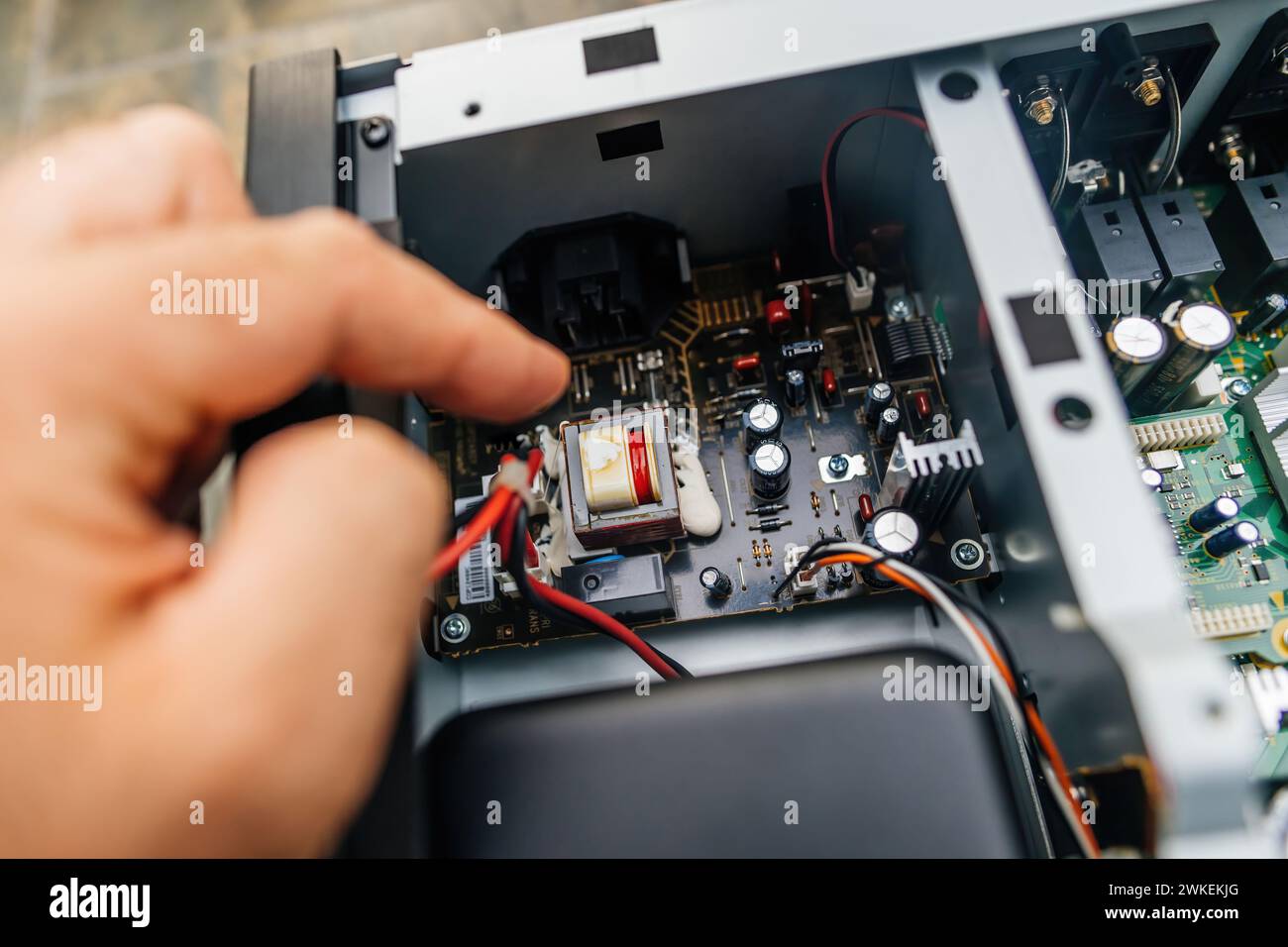 A male hand meticulously tests and repairs a powerful music amplifier ...