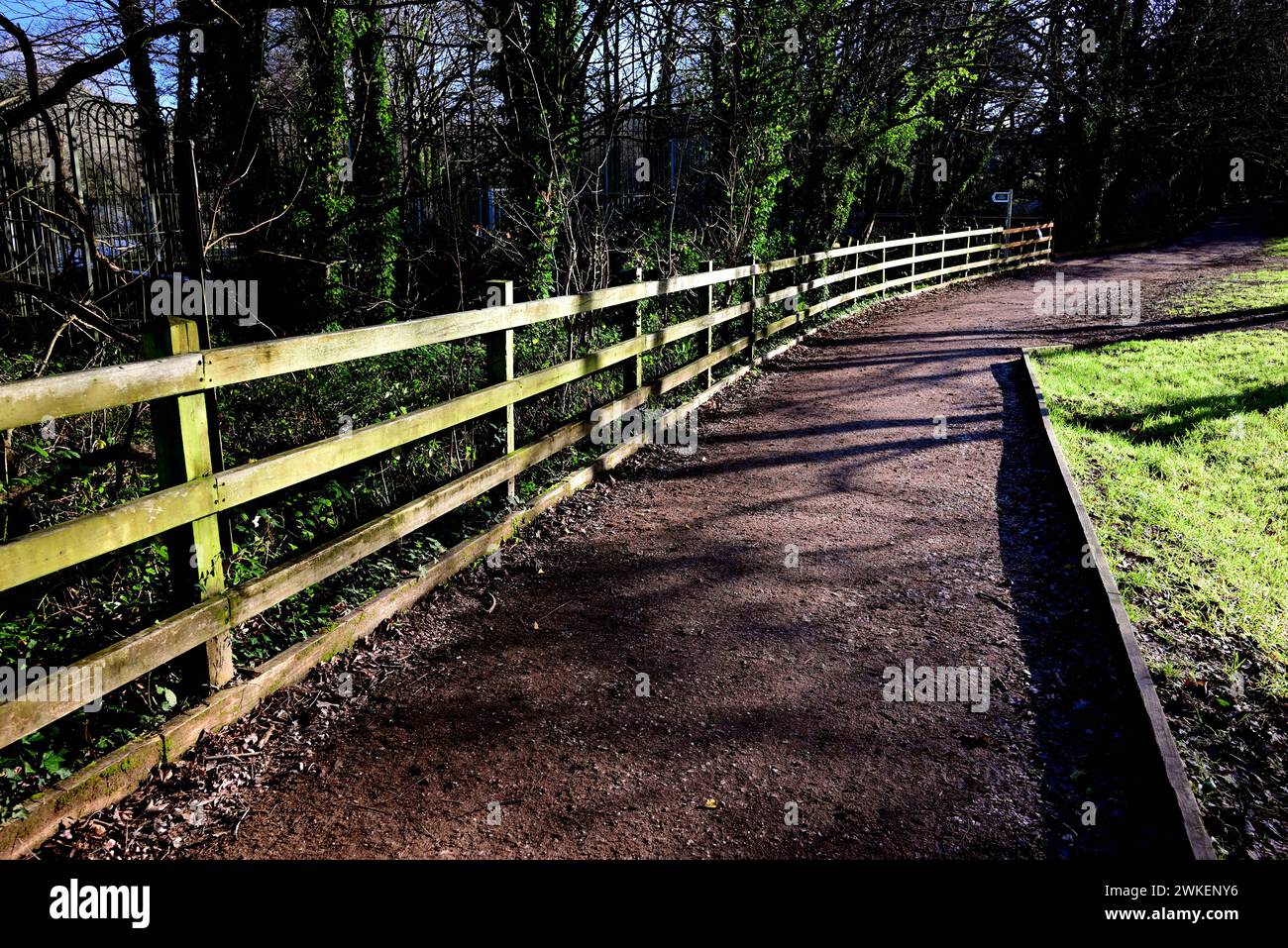 A fence beside a shared footpath/cycle path, sunlit by the low angle of ...