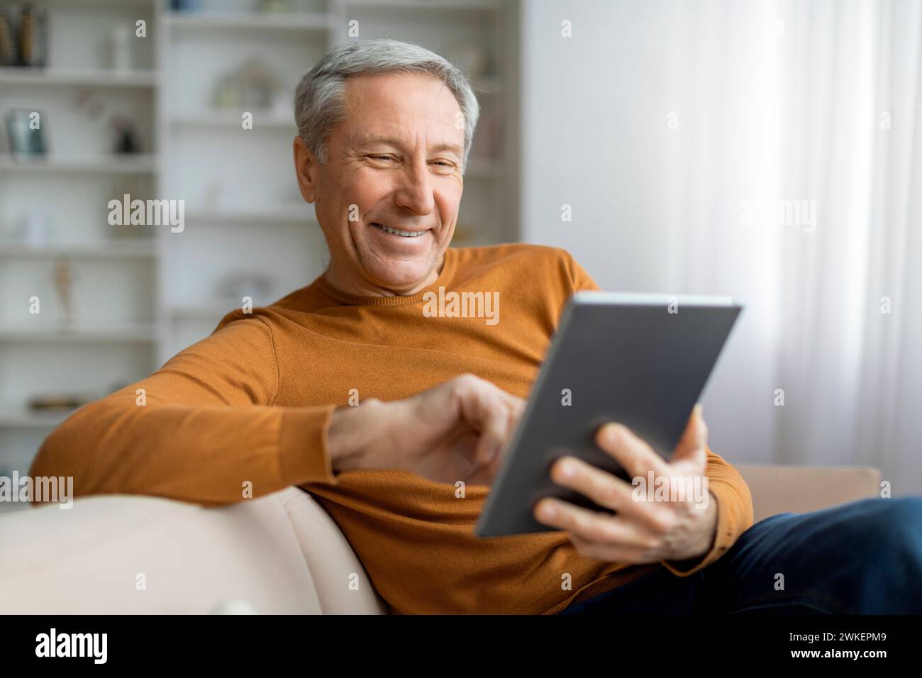 Happy senior man chilling at home, using tablet Stock Photo - Alamy