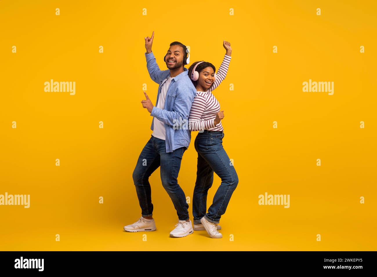 Young black couple wearing wireless headphones dancing back-to-back on ...