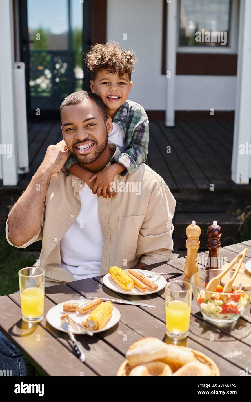 happy african american kid hugging father while having bbq on backyard ...