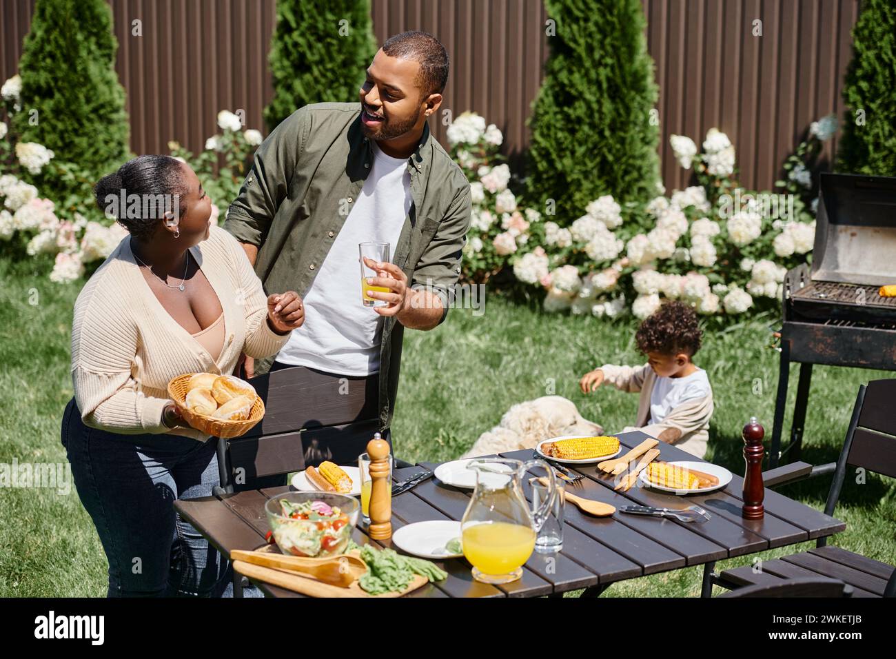 happy african american parents serving table in garden near son playing ...
