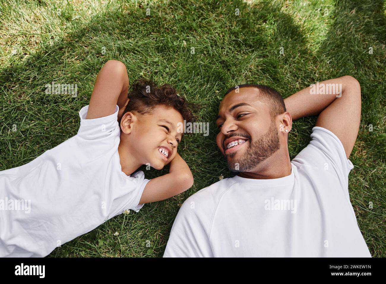 top view of cheerful african american father and cute son lying on ...