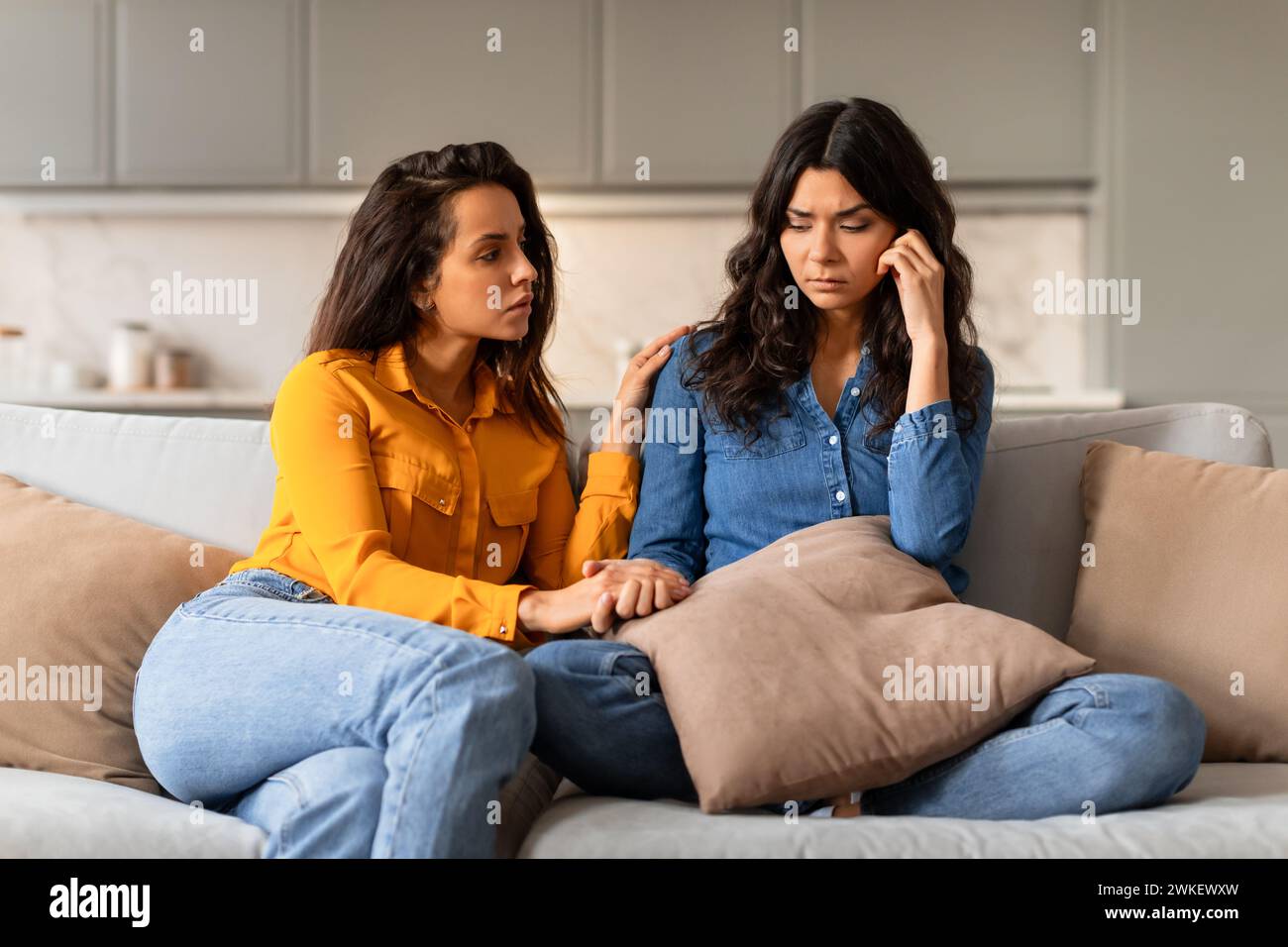 Attentive young woman comforting depressed friend sitting on couch ...