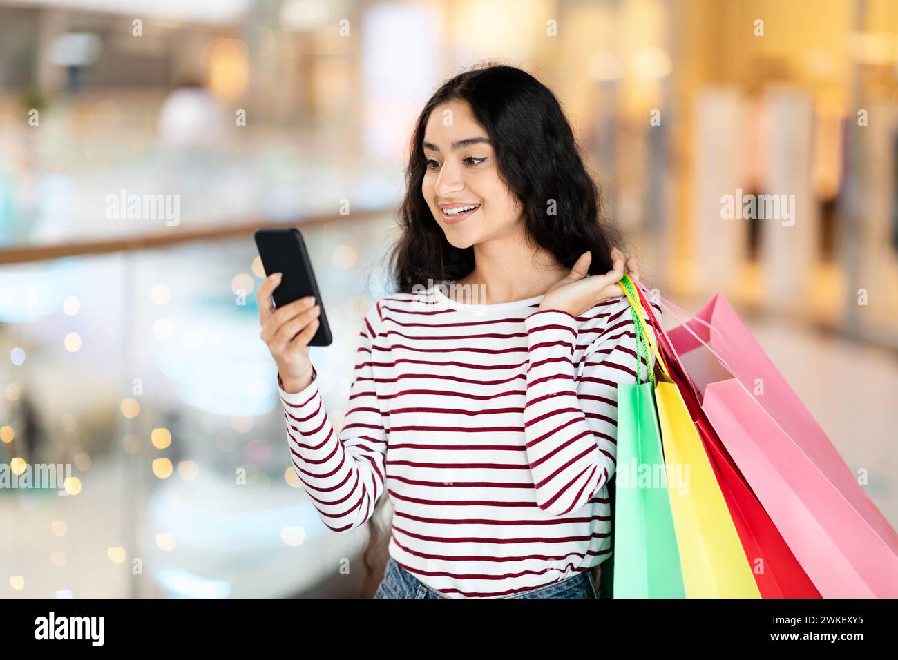 Happy young indian lady shopping at mall, using phone Stock Photo - Alamy
