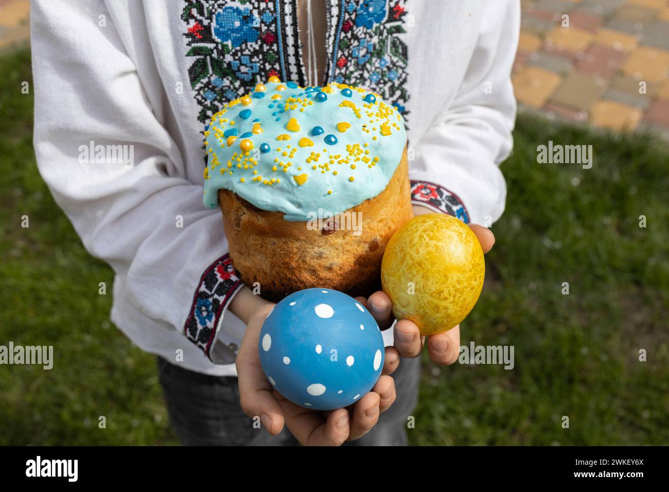 yellow-blue eggs and Easter homemade Easter cake in the hands of a Ukrainian child in an ...