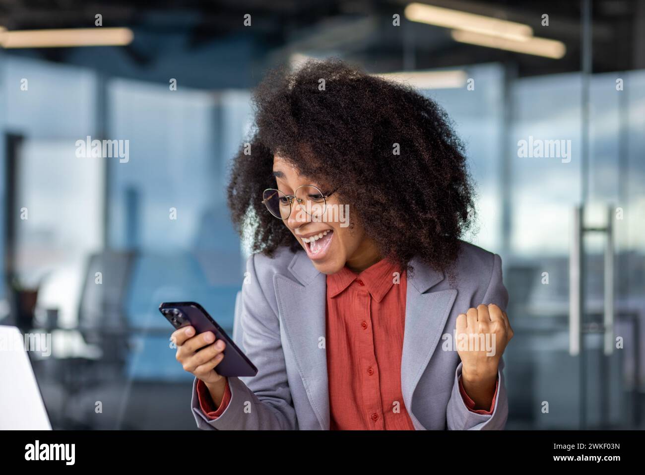 Excited hispanic office manager raising hand with clenched fist while ...