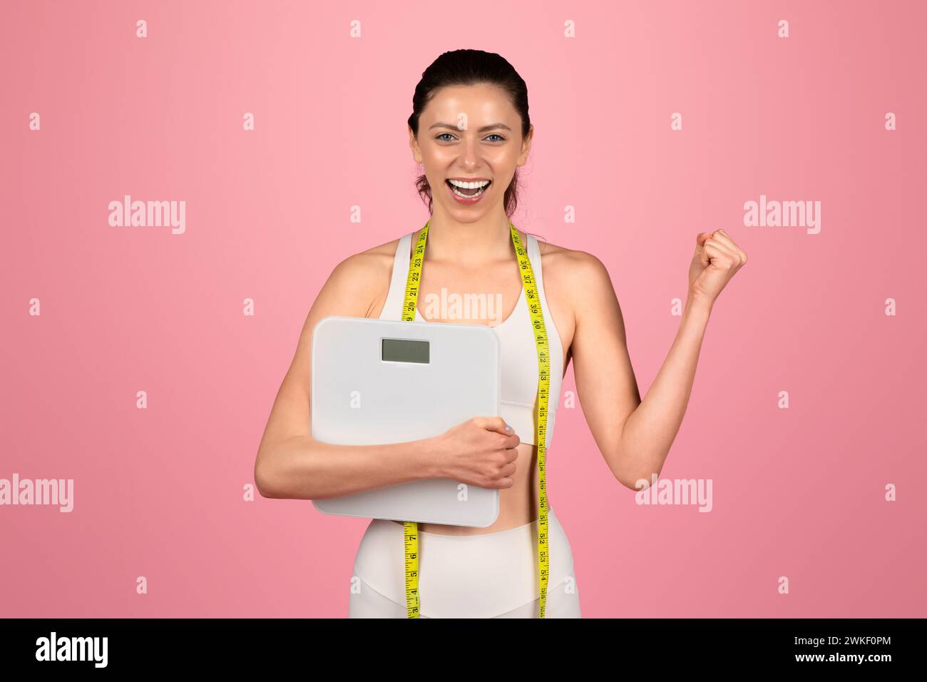 Exultant young woman celebrating her weight loss success, holding a ...