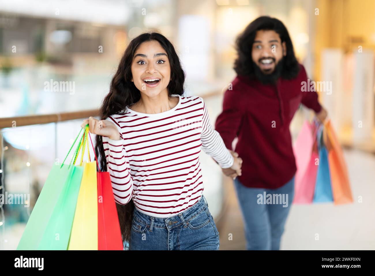 Excited young indian woman running by mall, pulling her boyfriend Stock ...