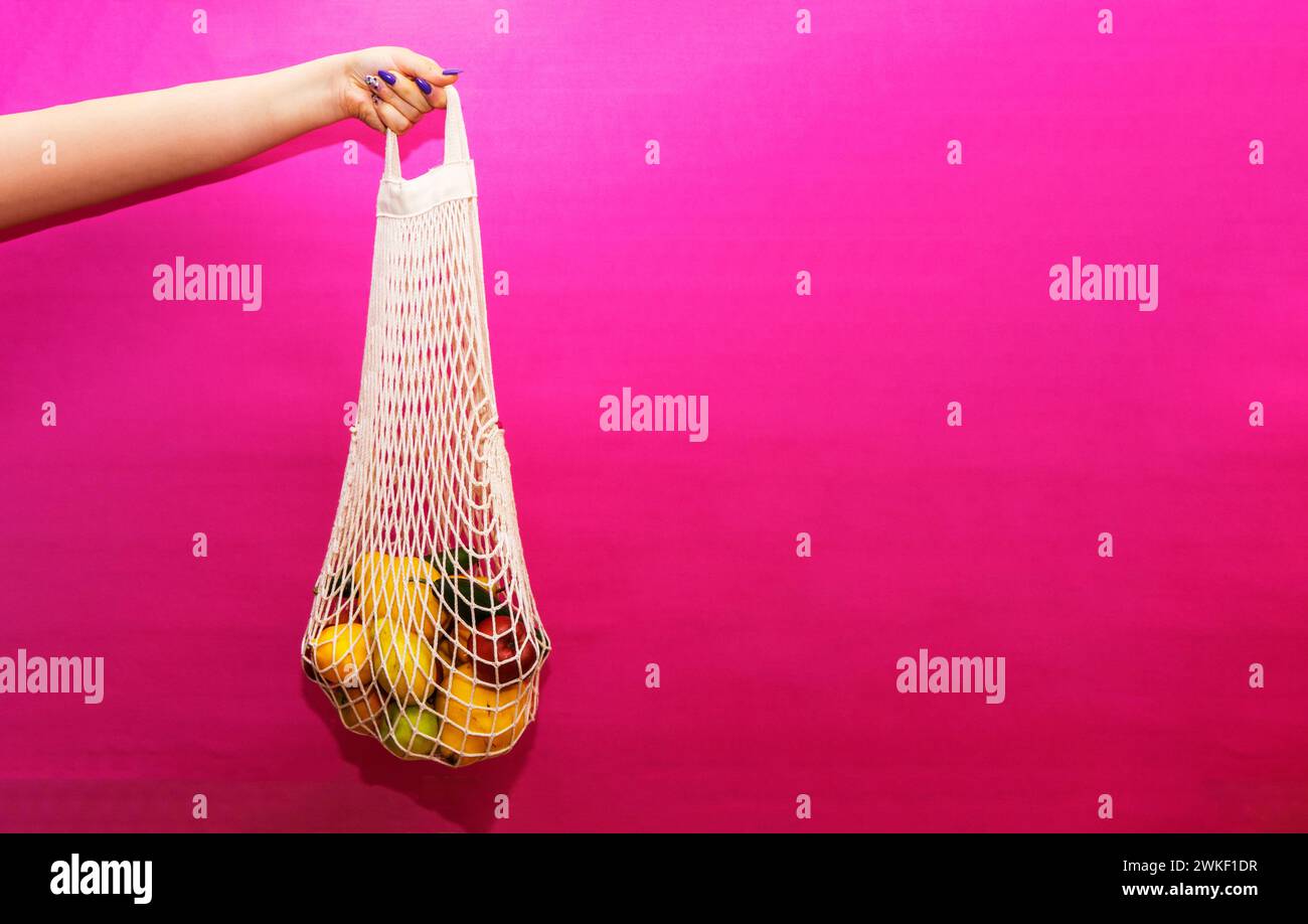 Women hand holds white string bag with different vegetables and fruits ...