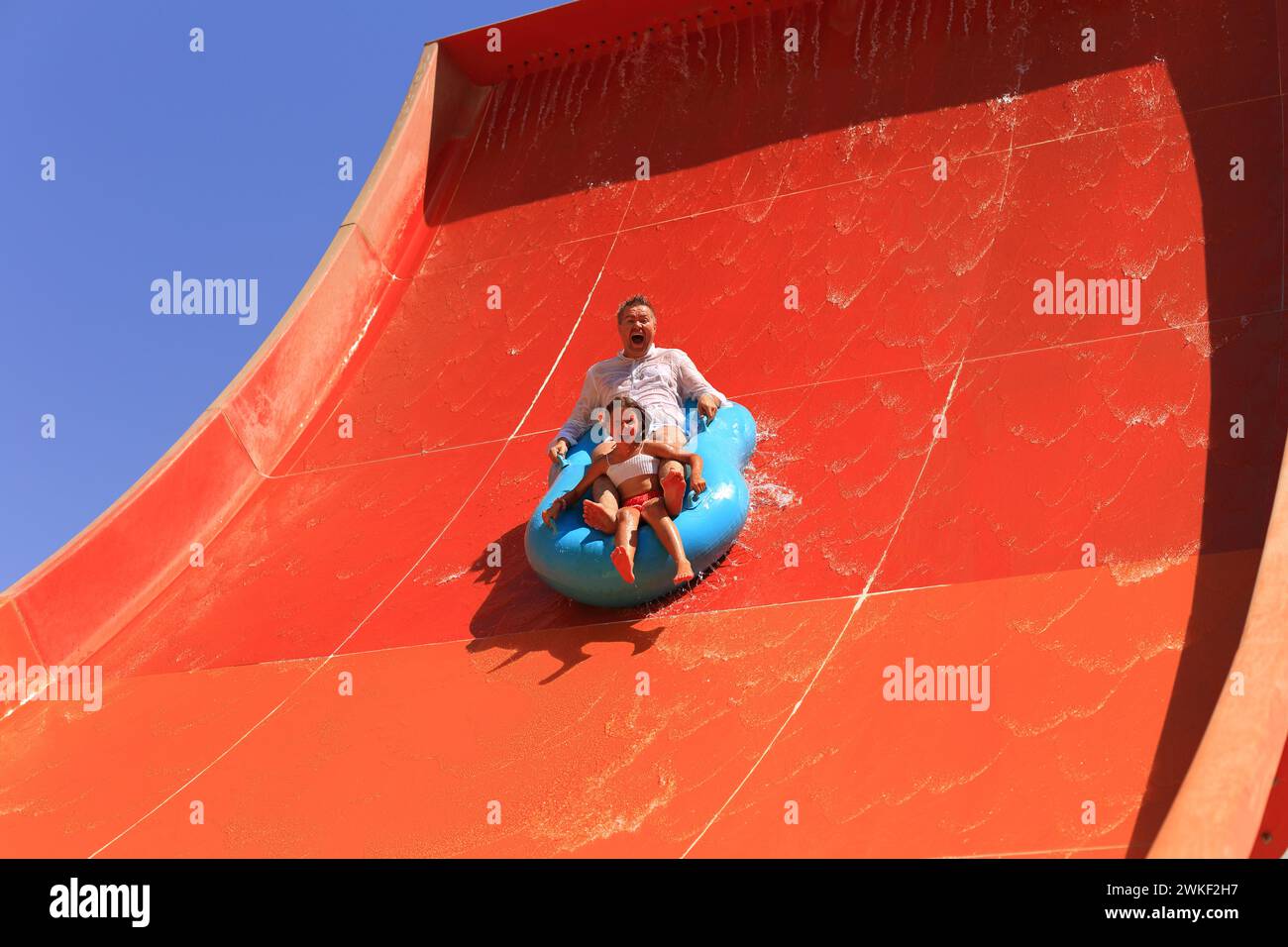 Family going down a water slide at a water park in summer. Father and ...