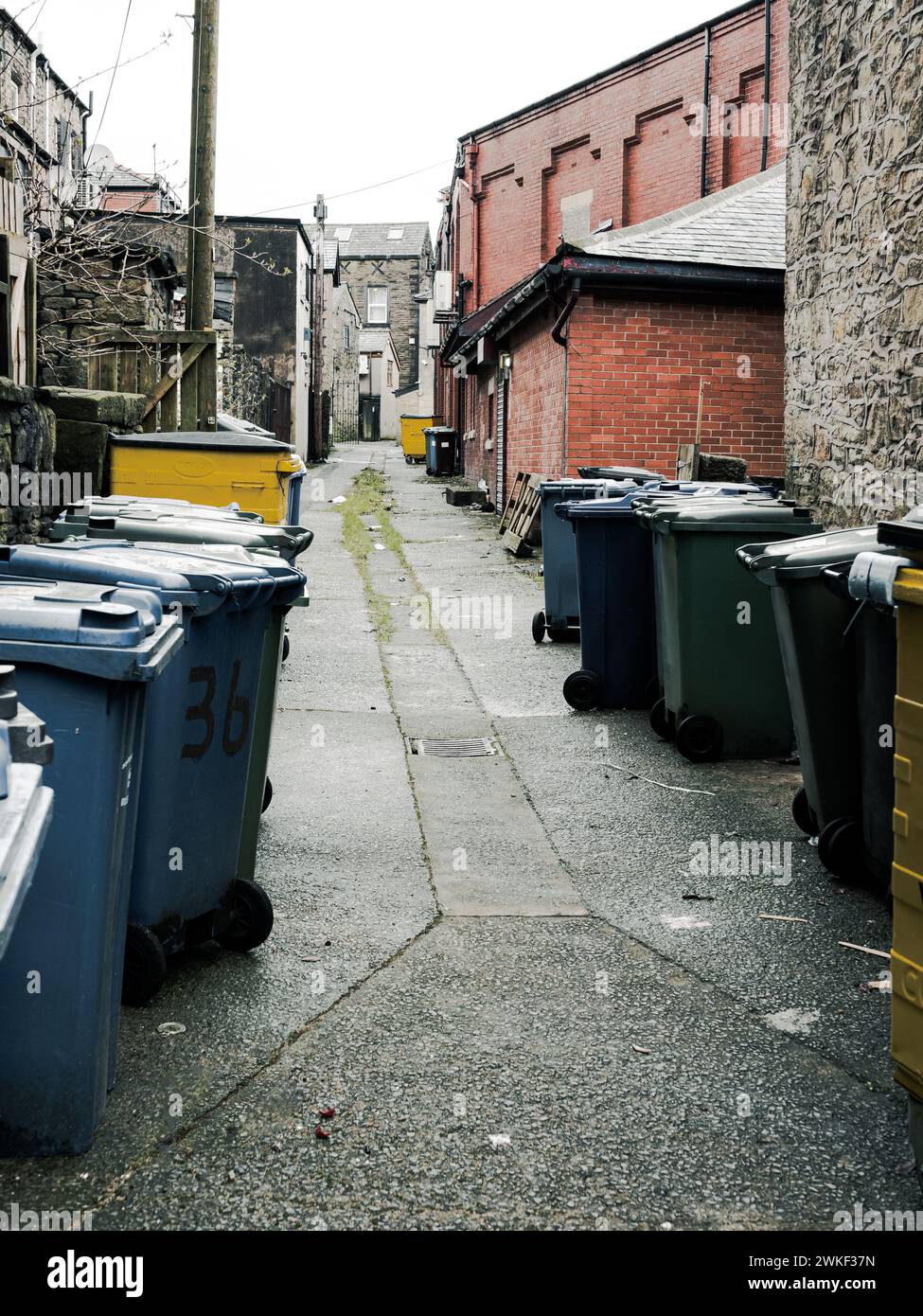 Dark and damp back alleyway of a northern town in England UK with lines ...
