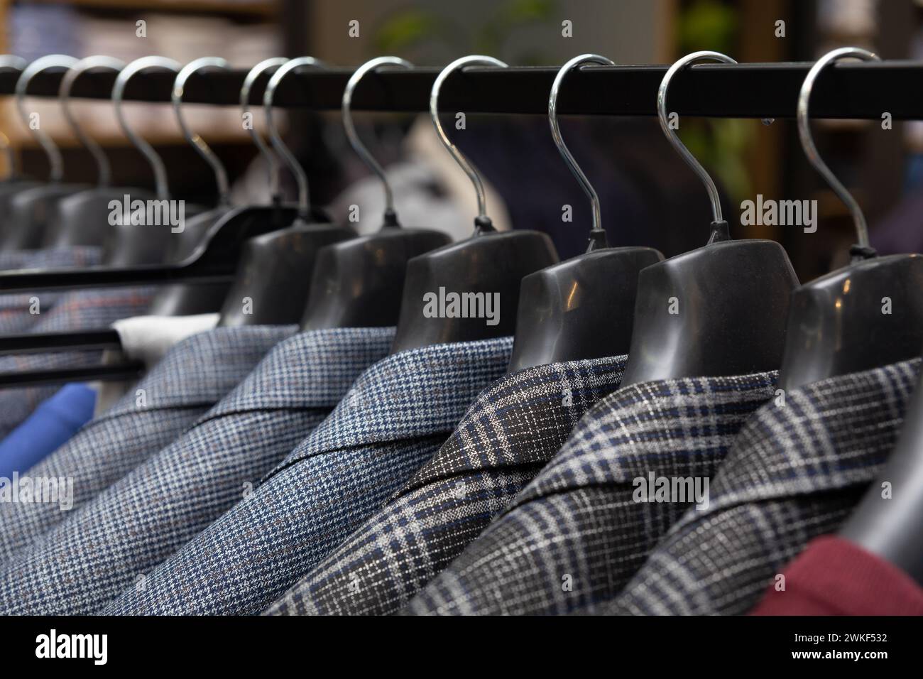 A row of men's suits, jackets hanging on a rack for display. Elegant ...