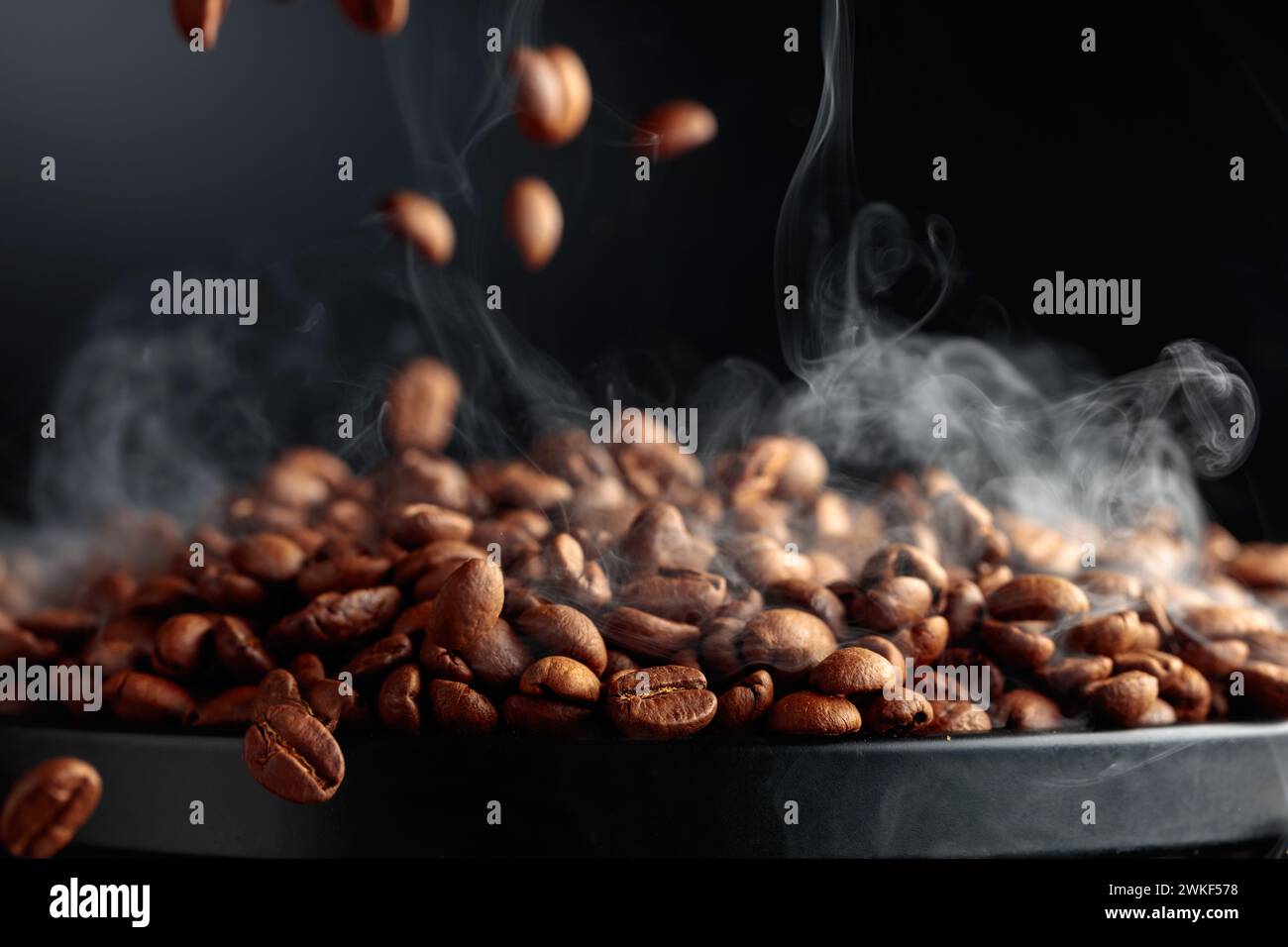 Steaming coffee beans in movement on a black background Stock Photo - Alamy