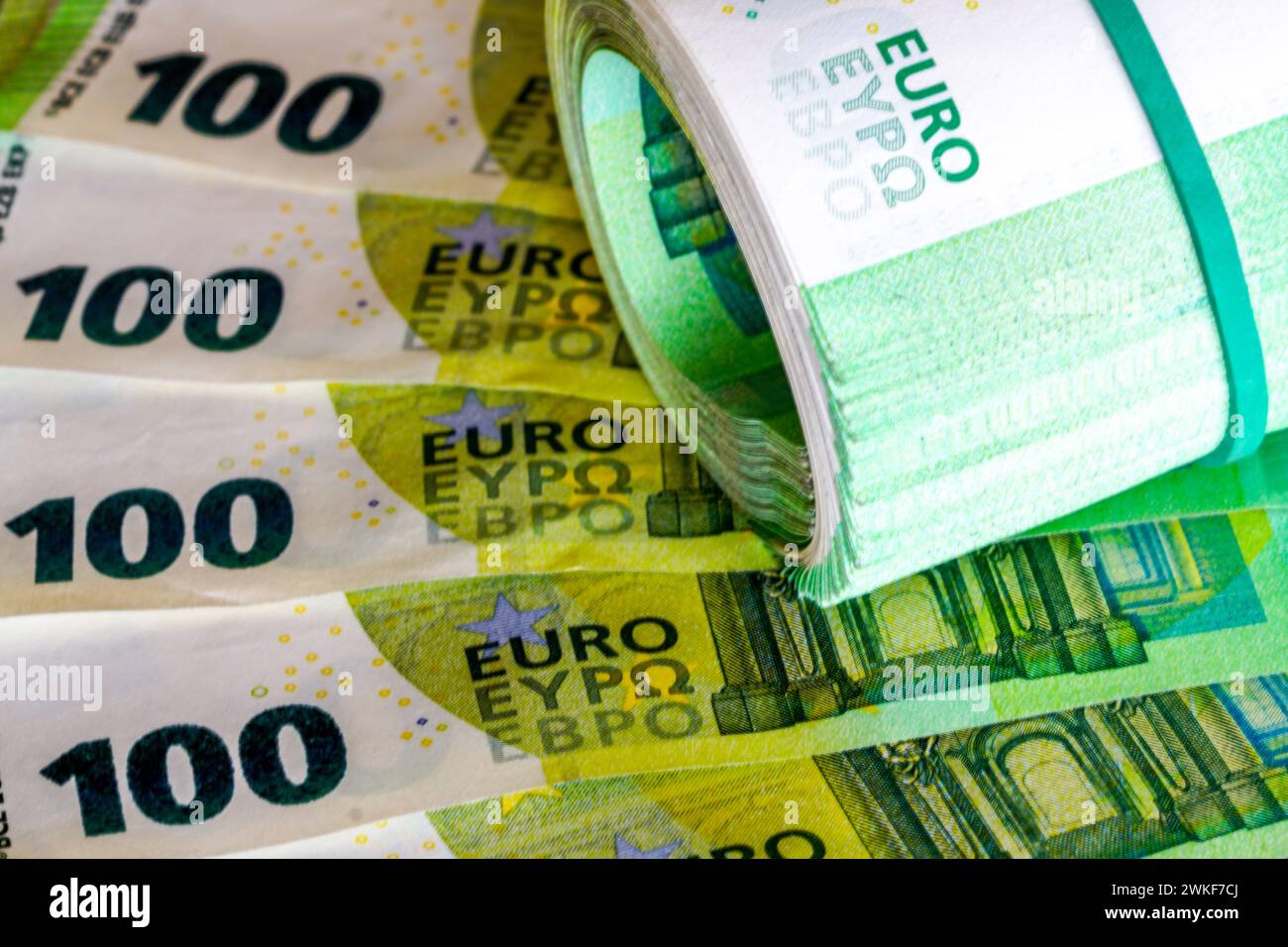 A roll of one hundred euro banknotes with a green rubber band on a ...