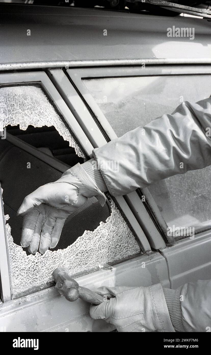 1970s, historical, car theft, a glove hand knocking out the smashed ...
