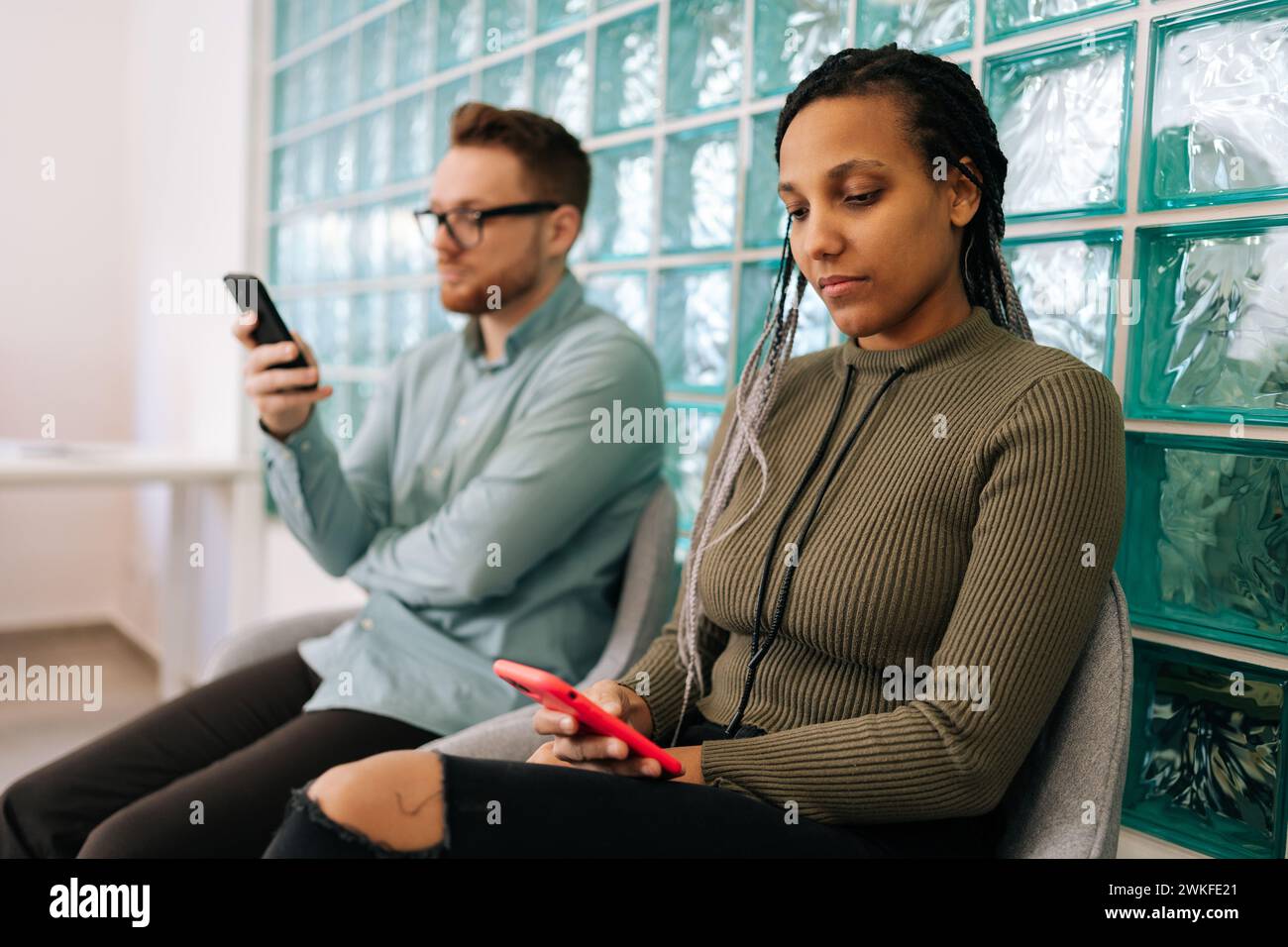 Two diverse young business people, hiring, using mobile phones in ...