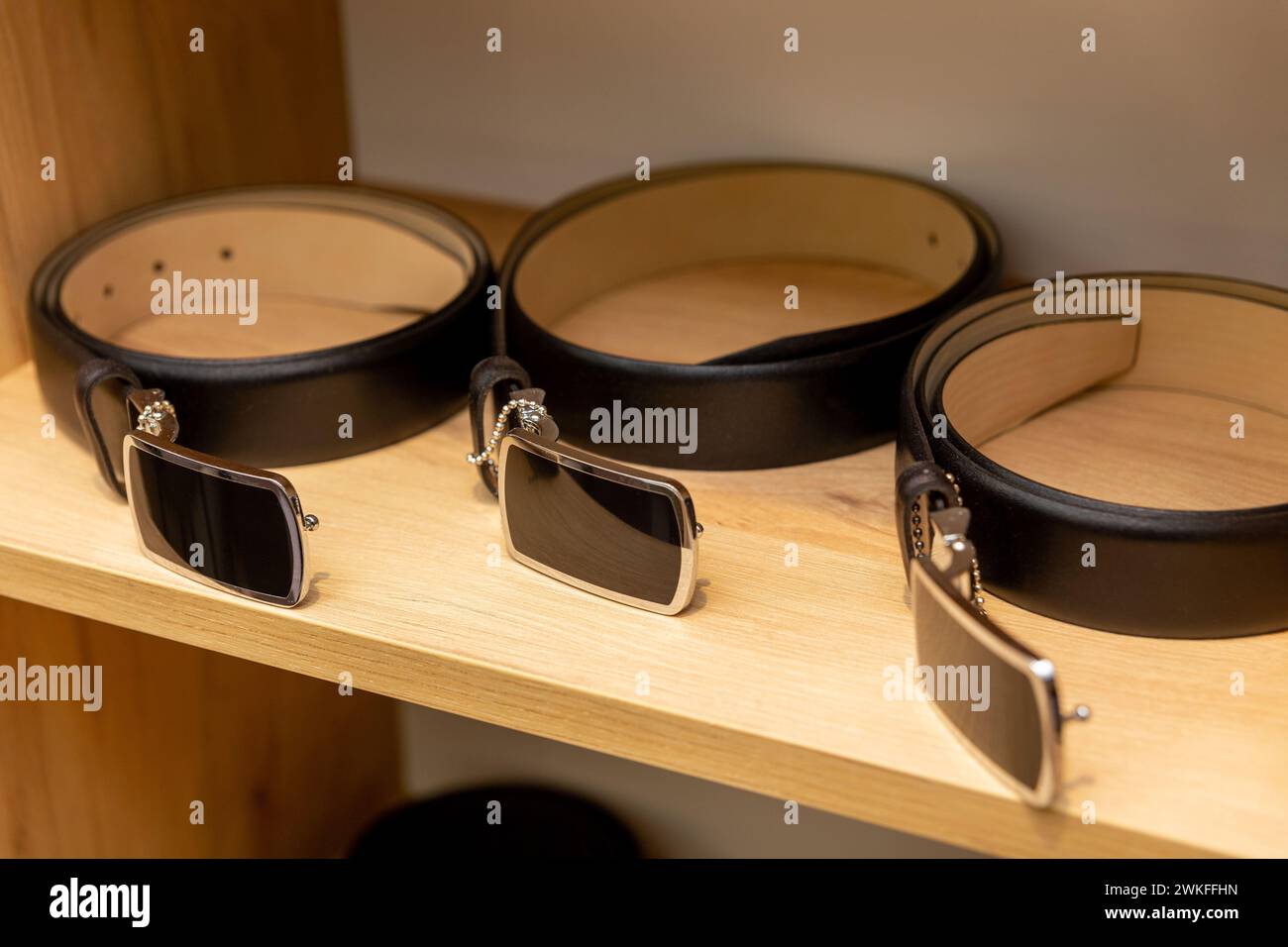 Black leather belts display on shelf in the store in a men clothing ...