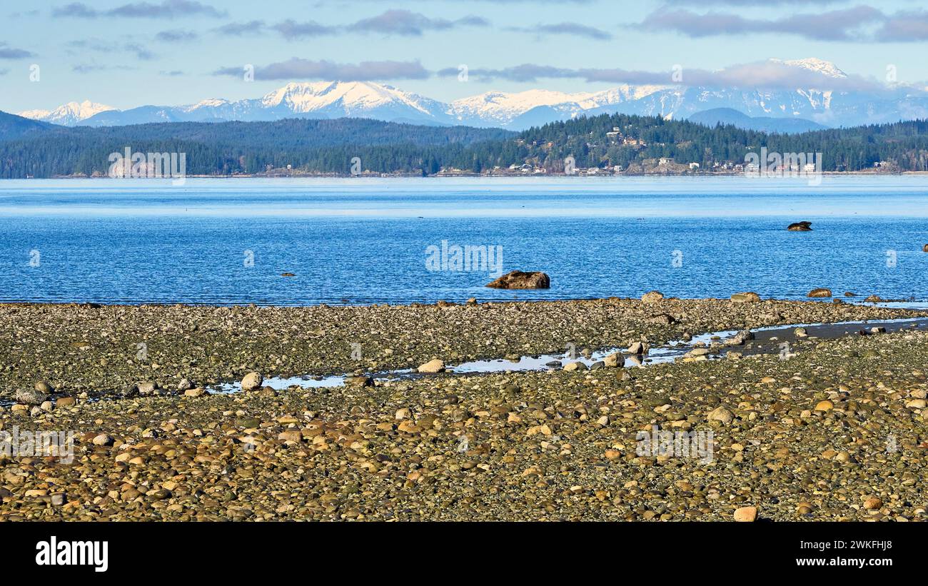 View from a rocky beach acroos the ocean strait to distant islands and ...