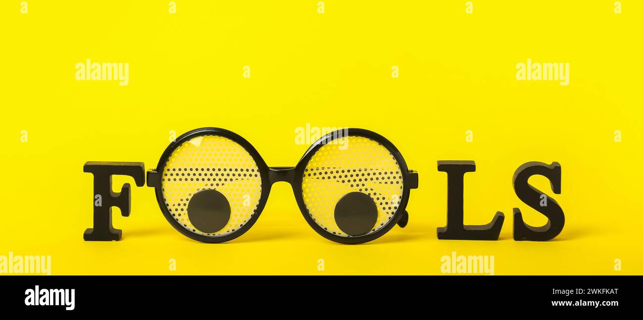 Word FOOL'S made of letters and eyeglasses on yellow background. April ...