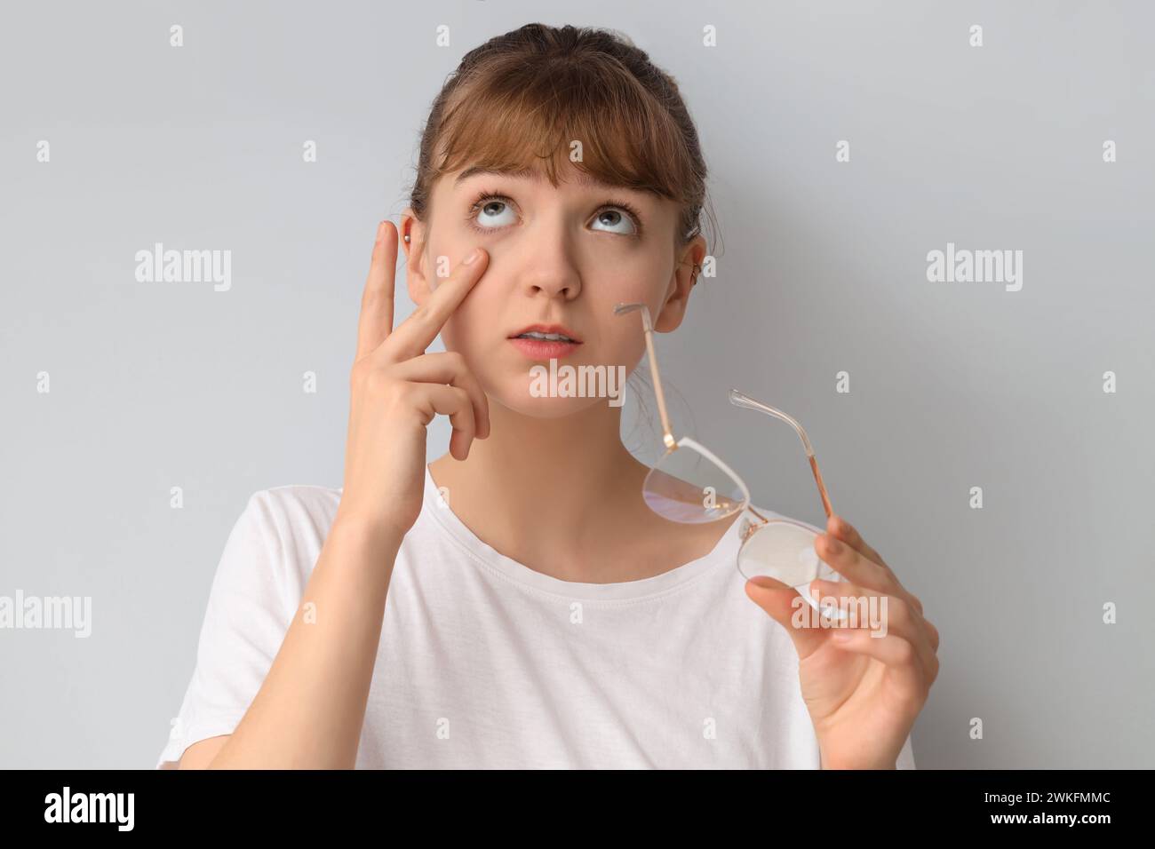 Young woman with eyeglasses on light background. Glaucoma awareness ...