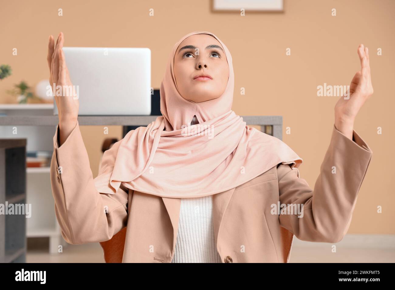 Young Muslim woman praying in office Stock Photo - Alamy