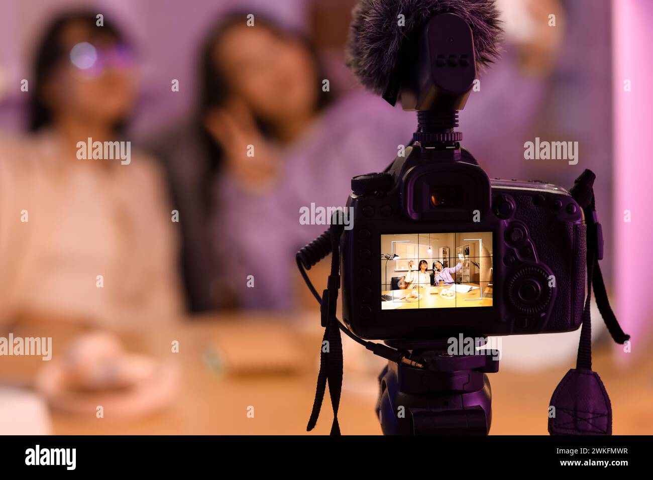 Female podcasters taking selfie on camera screen in studio at night ...
