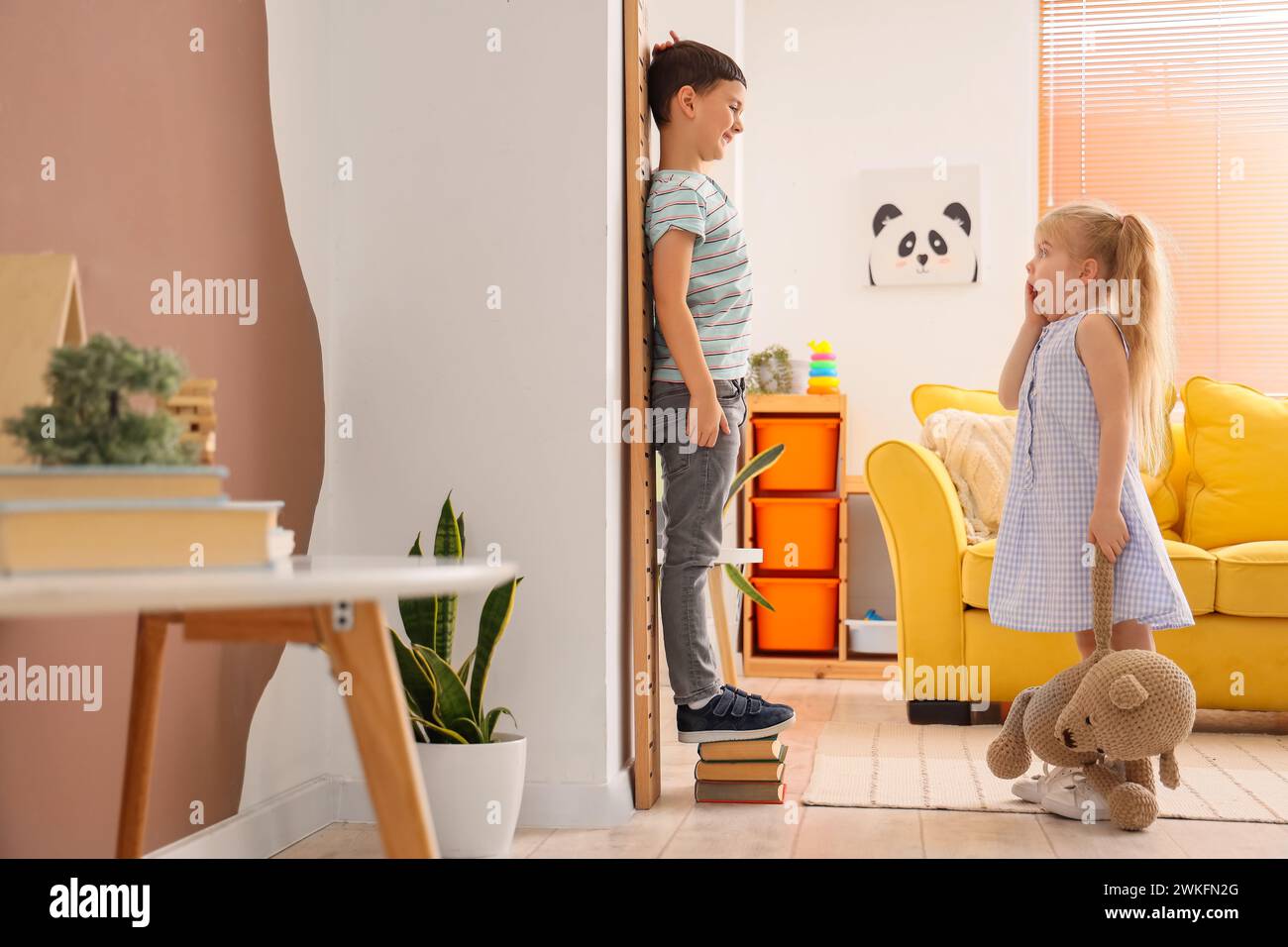 Cute little kids measuring height near wooden stadiometer at home Stock ...
