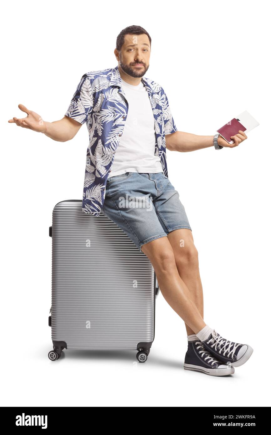 Confused male tourist holding a passport and sitting on a suitcase ...