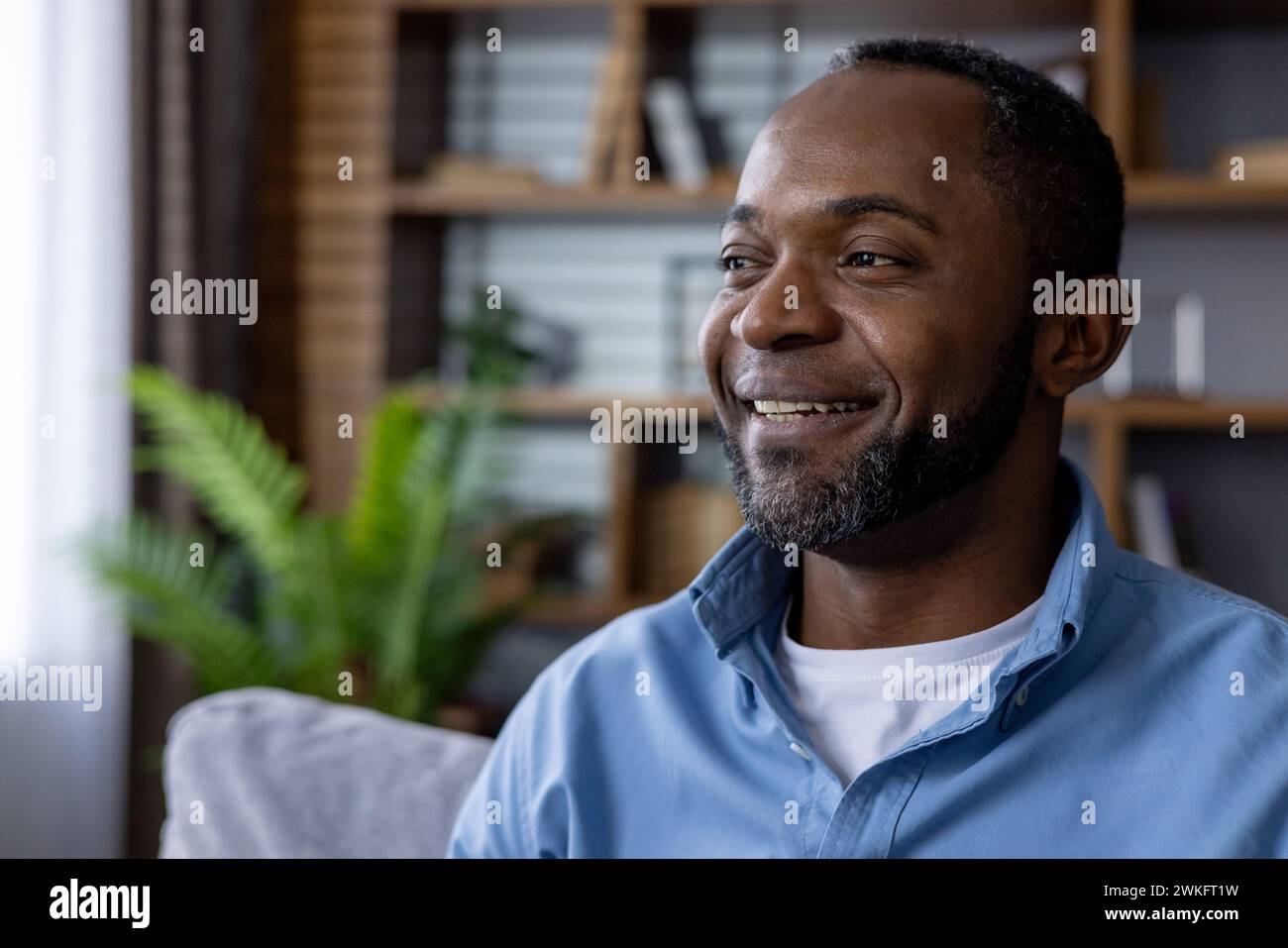 Happy African American male with a subtle smile sitting in a cozy indoor setting. The image ...