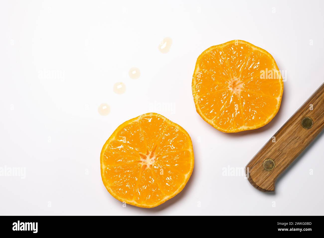 Split oranges against white background. Wooden knife handle and juice ...
