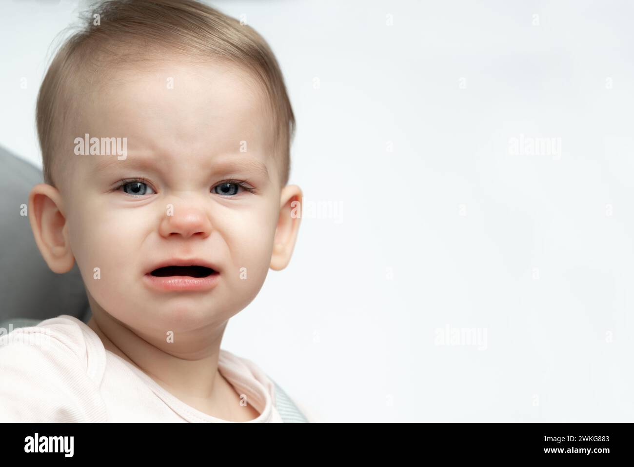 a baby is crying while sitting in a chair Stock Photo - Alamy