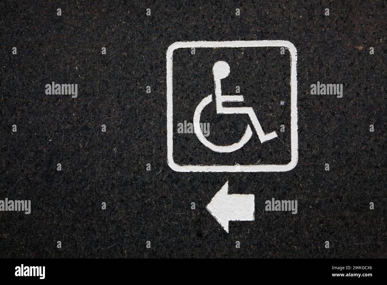 Close-up of handicap pictogram sign and white arrow engraved on black ...