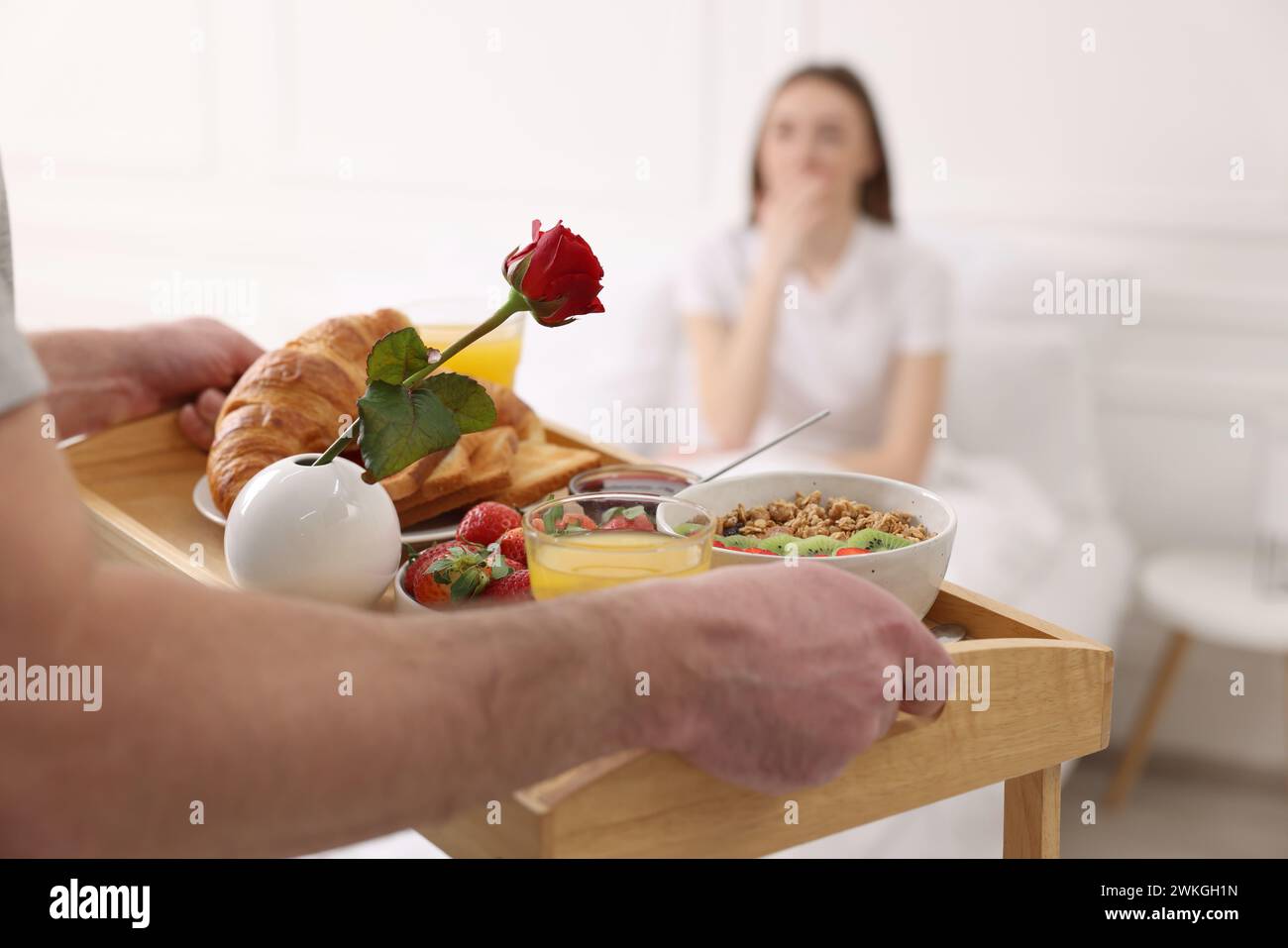 Romantic breakfast. Husband bringing tray with tasty food to his wife ...