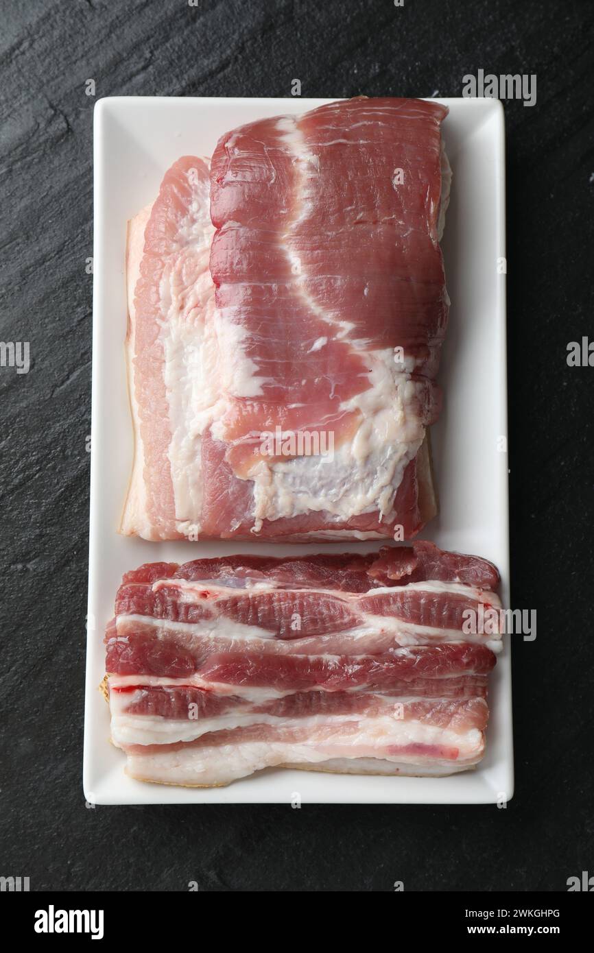 Pieces of raw pork belly on black textured table, top view Stock Photo ...