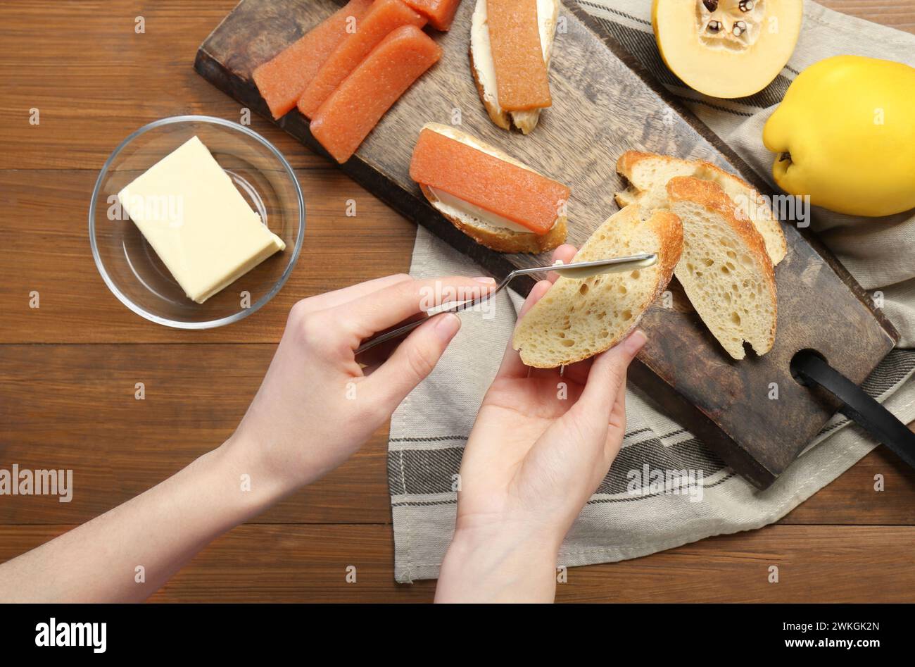 Making sandwich with quince paste. Woman buttering bread at wooden ...